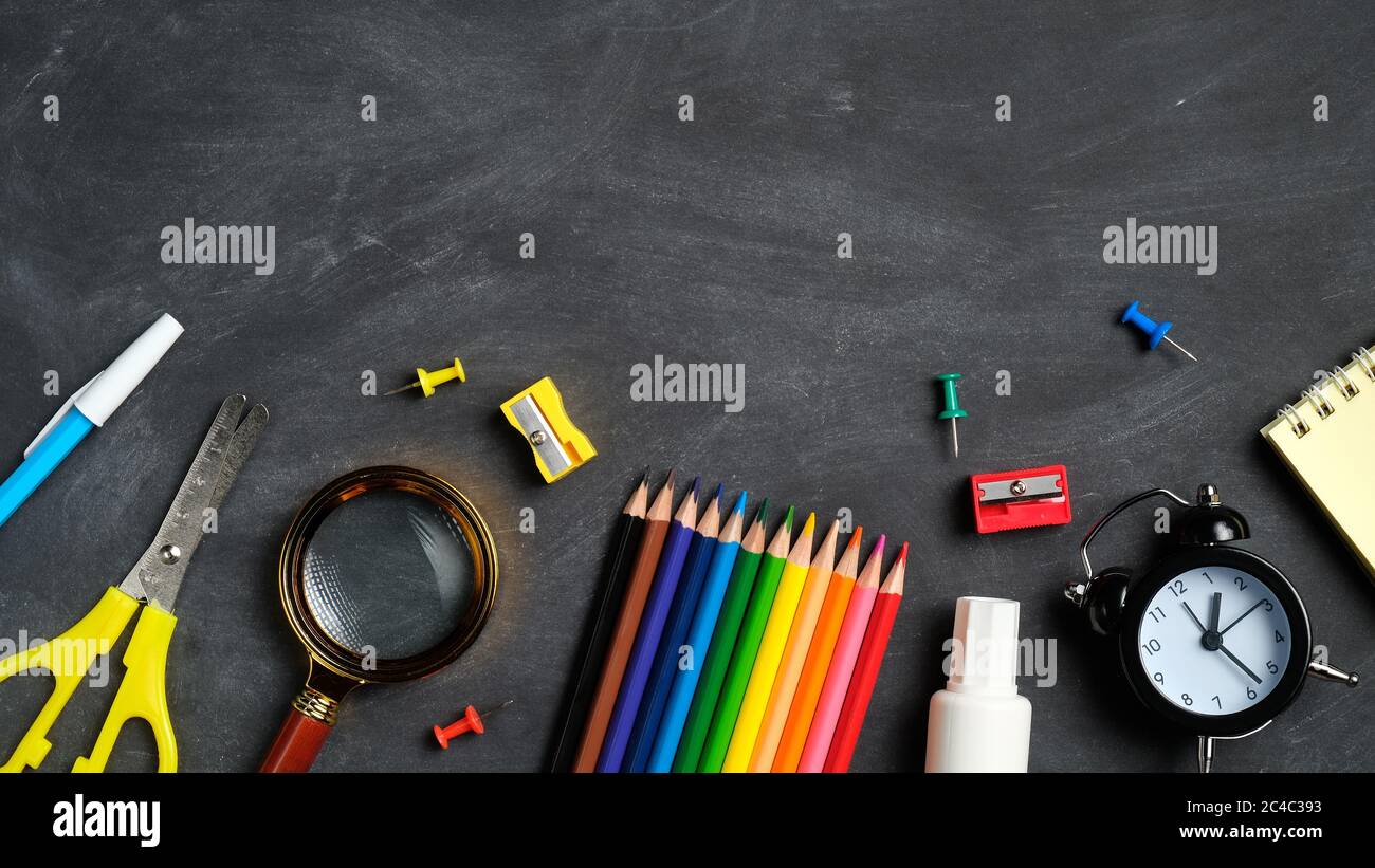 Flat lay school supplies on a blackboard background. Top view, overhead ...