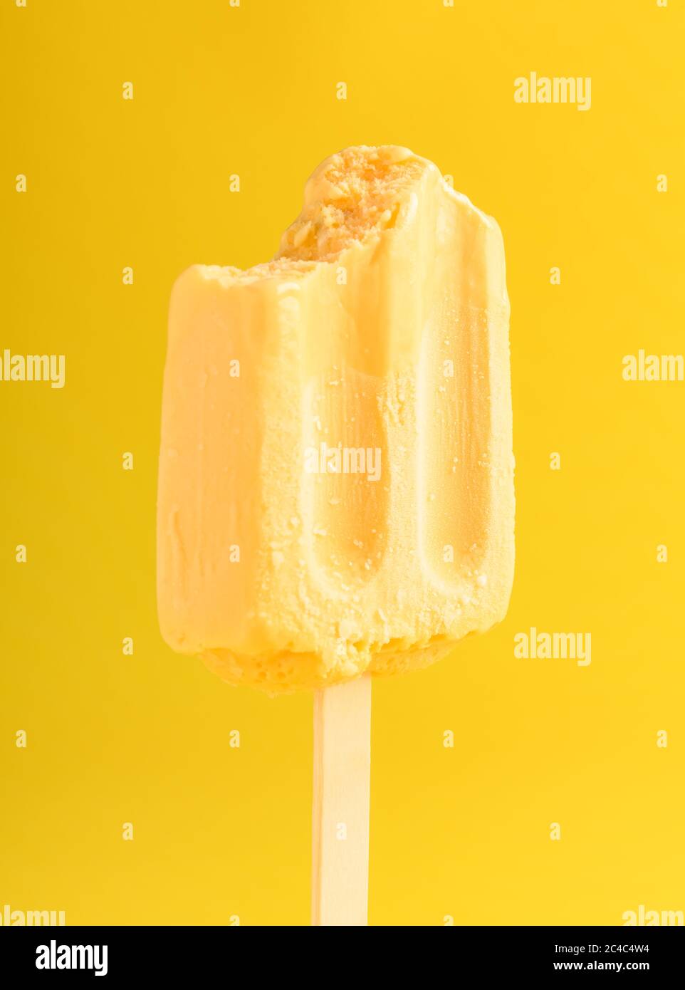 half eaten mango pudding flavor popsicle on a yellow background Stock ...