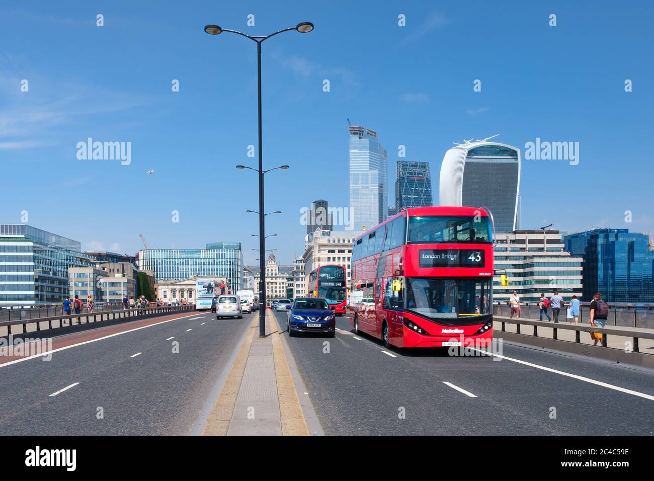 Typical double decker buses on the London Bridge with a view of the ...
