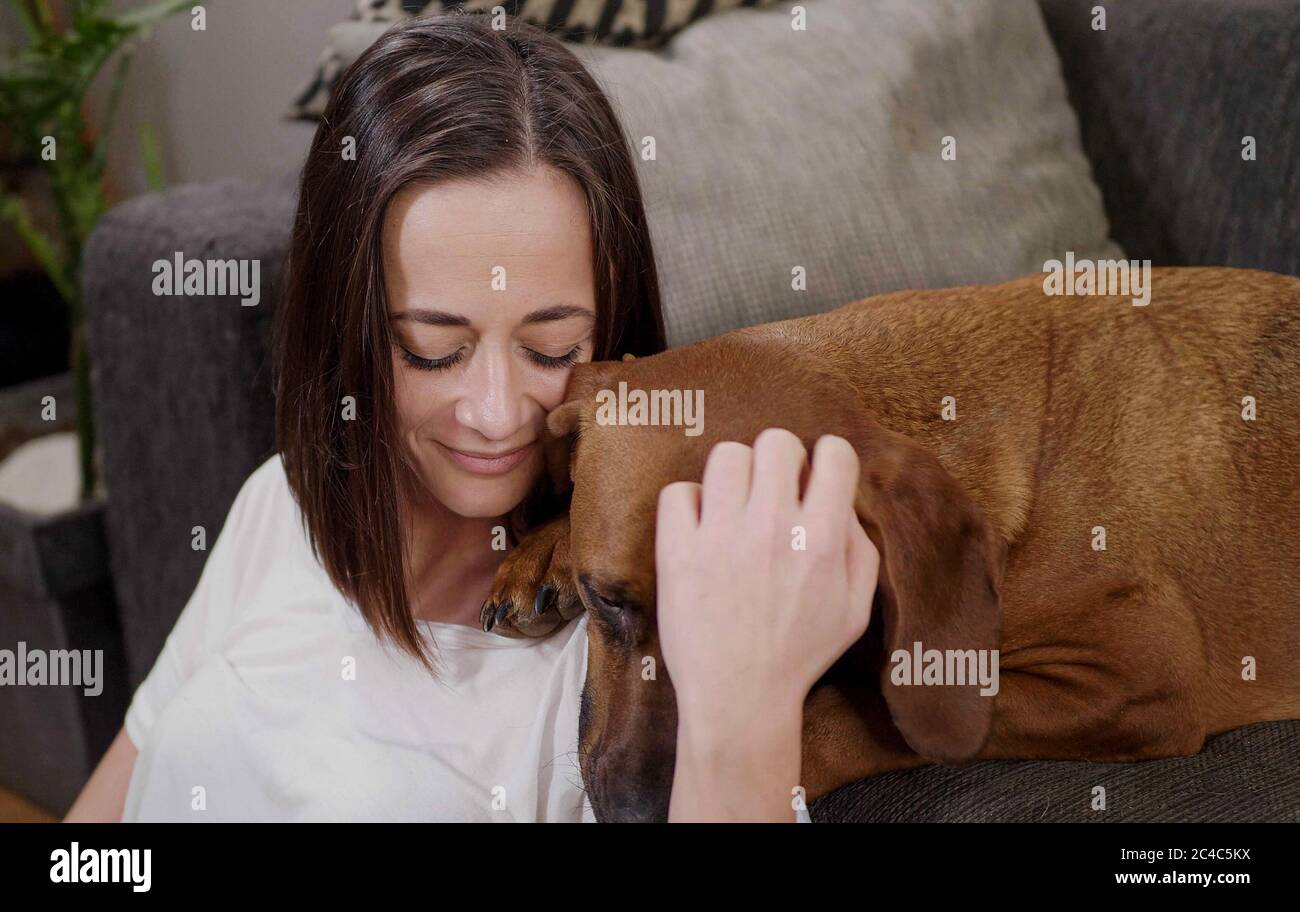 Young woman pets her dog while relaxing in the living room Stock Photo ...