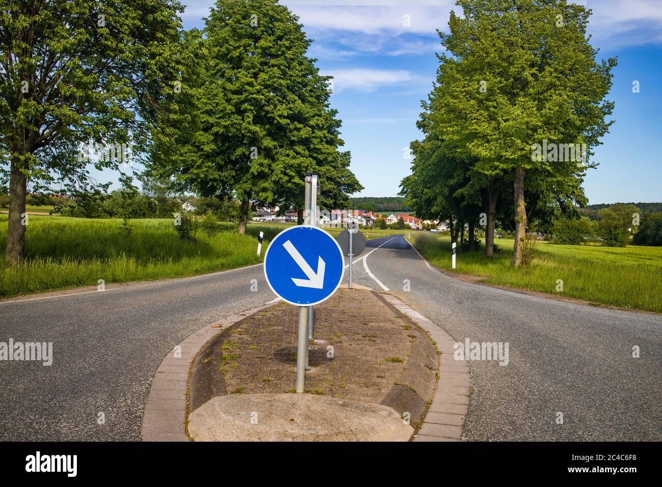 Country road with blue traffic sign and trees in summer in Germany ...