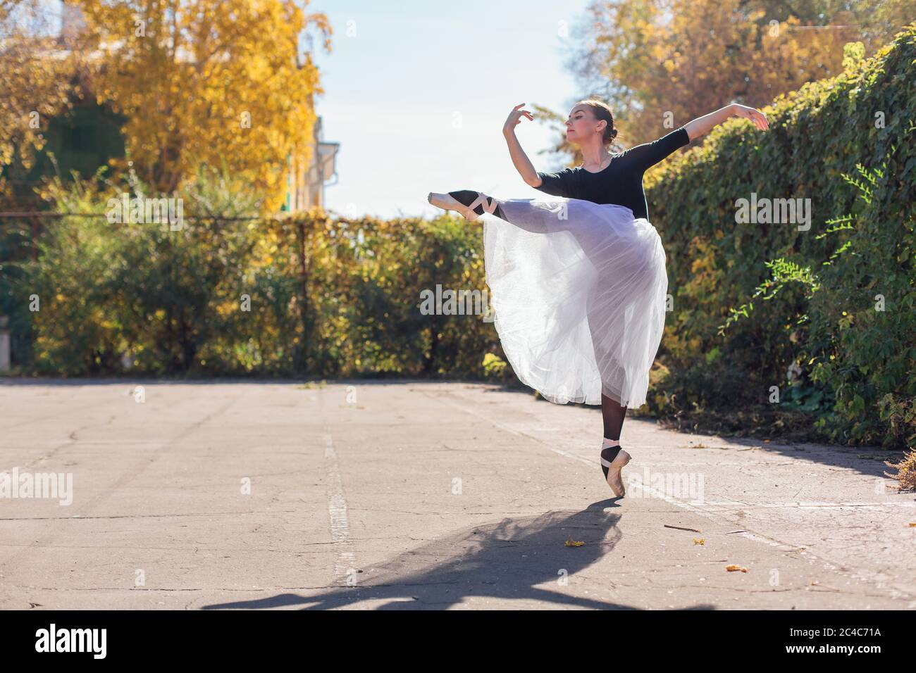 Woman ballerina in a white ballet skirt dancing in pointe shoes in ...