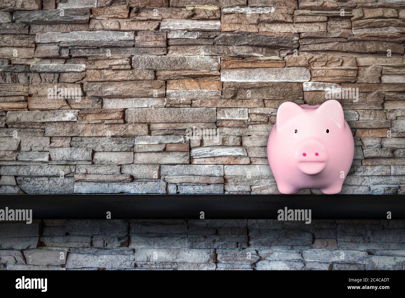 Piggy bank on shelf of stone brick wall background with copy space ...