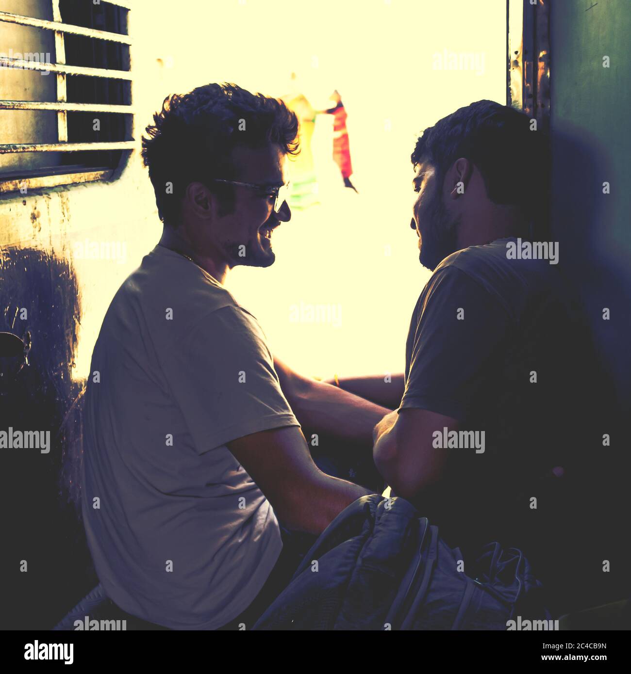 Two people enjoying their time sitting on the door of moving train ...