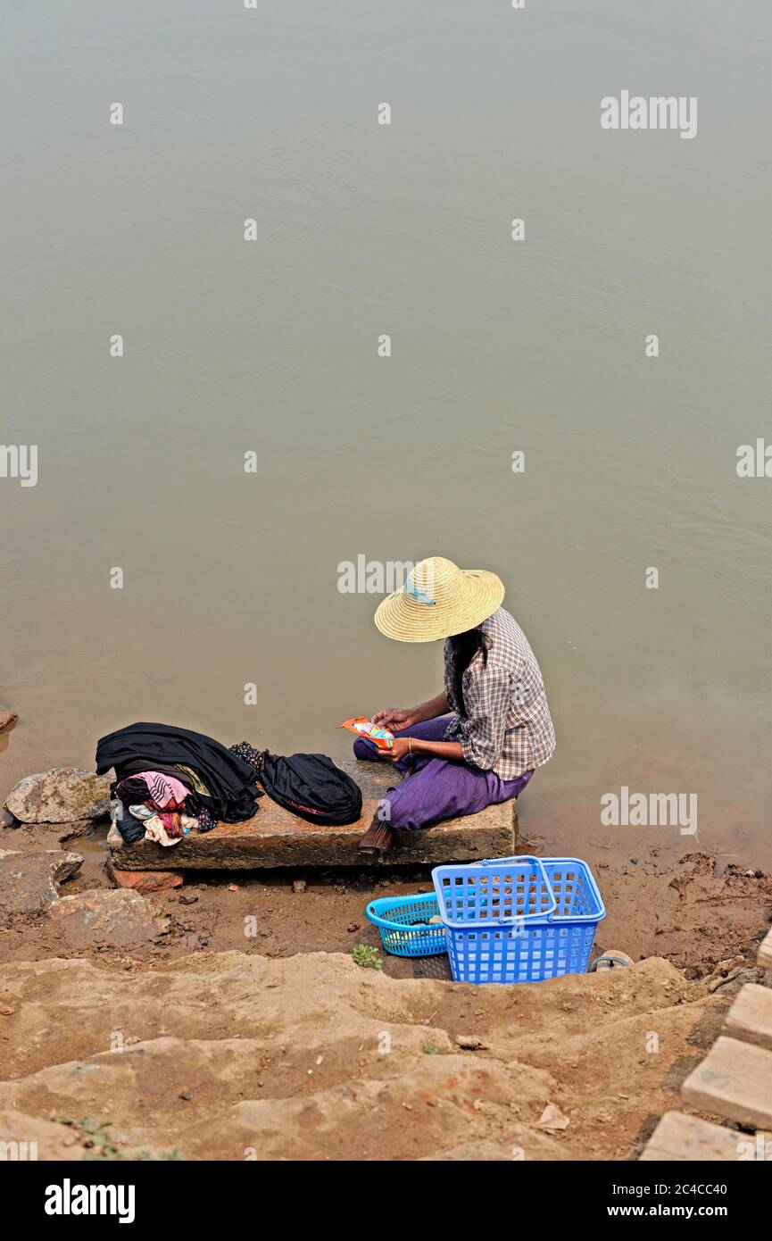 Woman washing clothes on the Irrawaddy River using ancient methods near ...