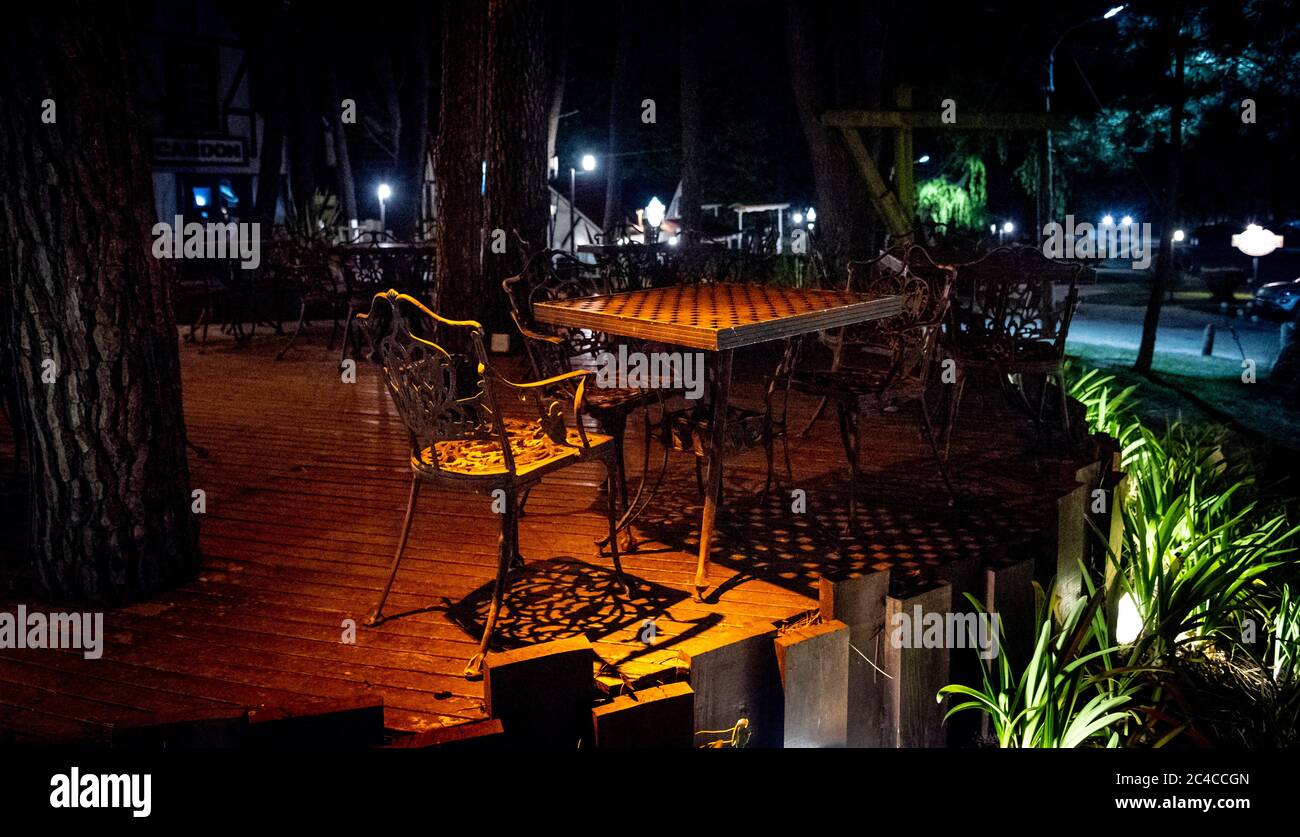Night scene of an isolated chair and table on a wooden deck of an ...