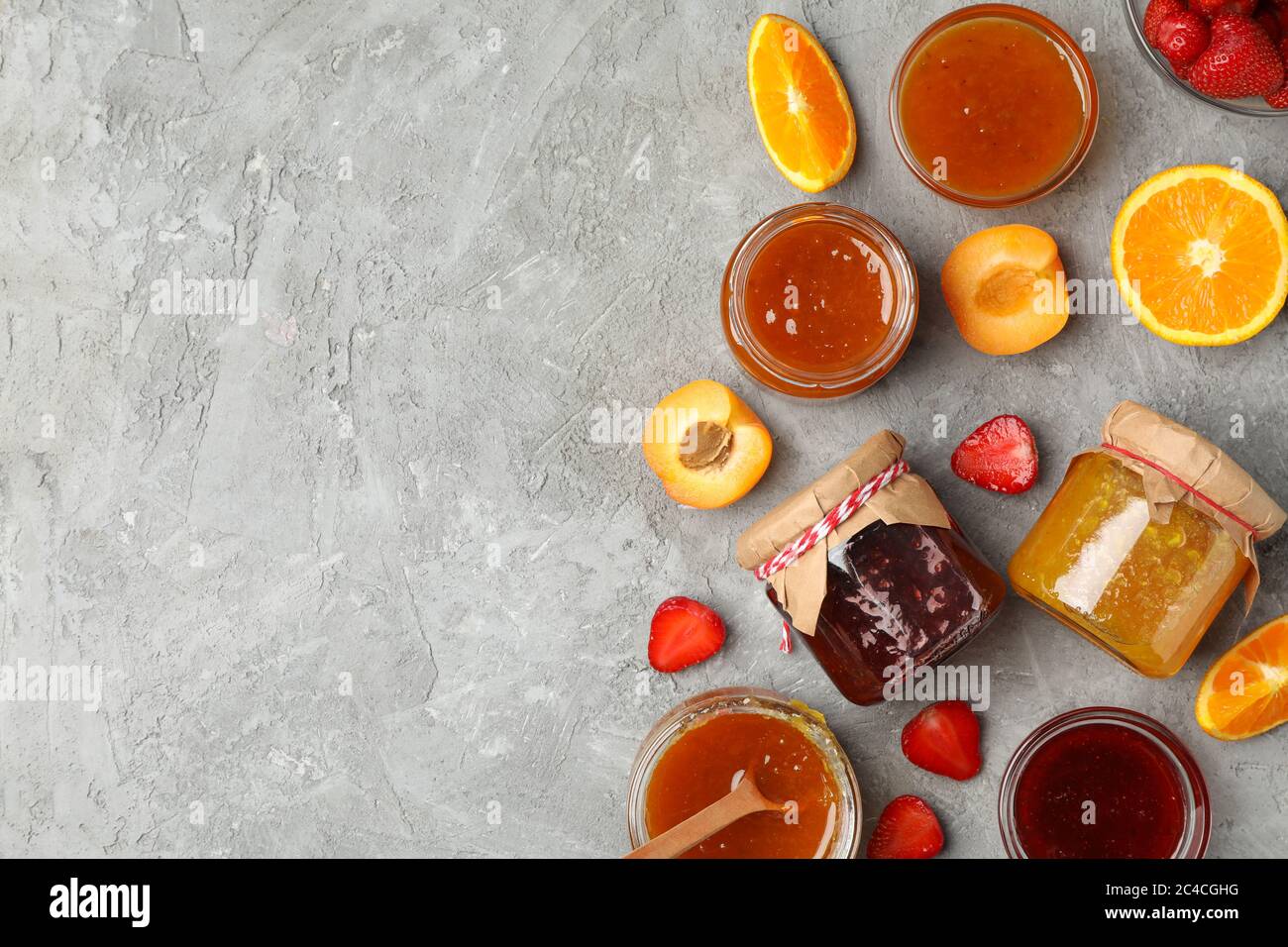 Glass jars with jam and ingredients on gray background, top view Stock ...