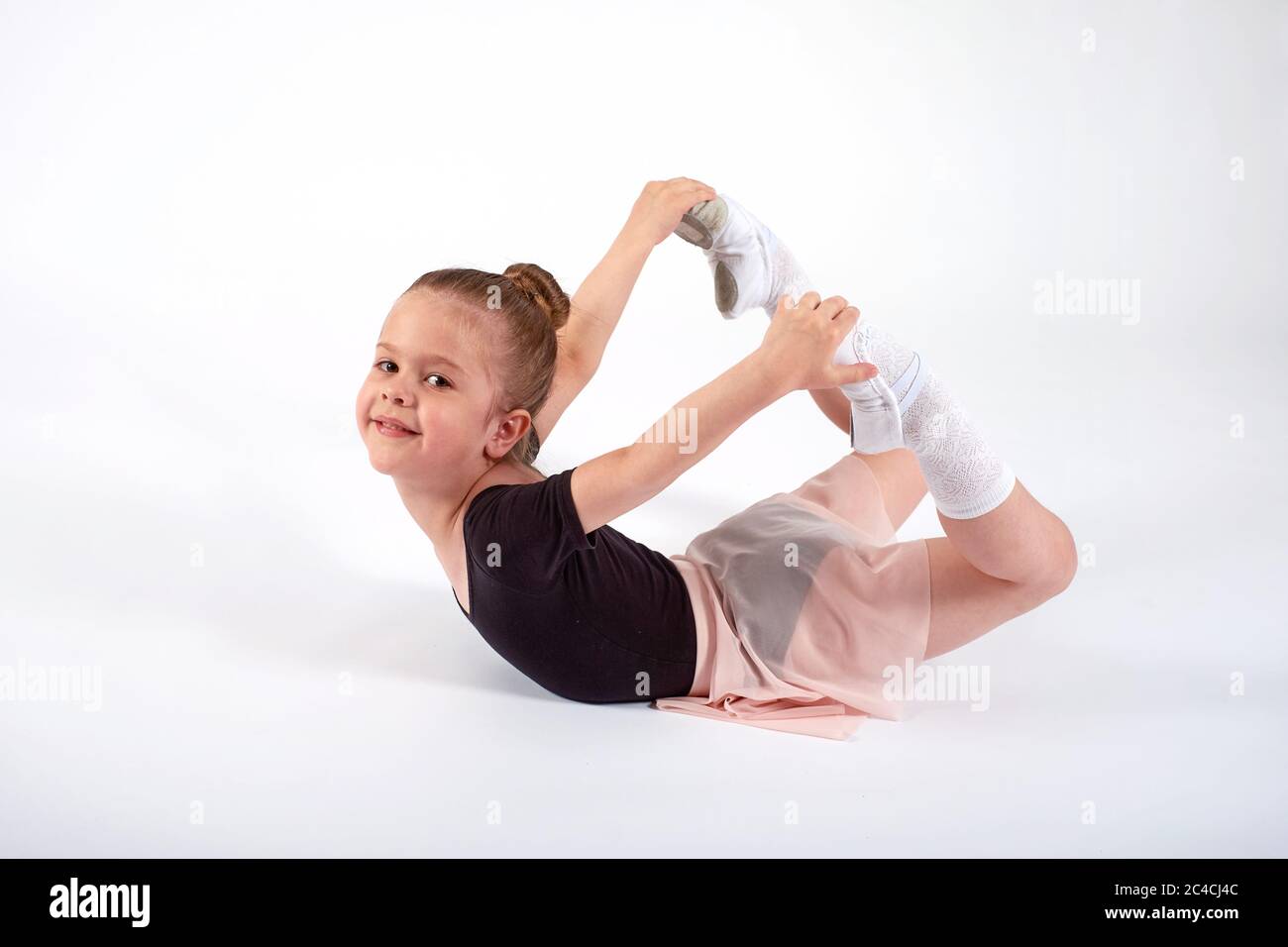 Little girl doing stretching and gymnastic exercises on a white ...