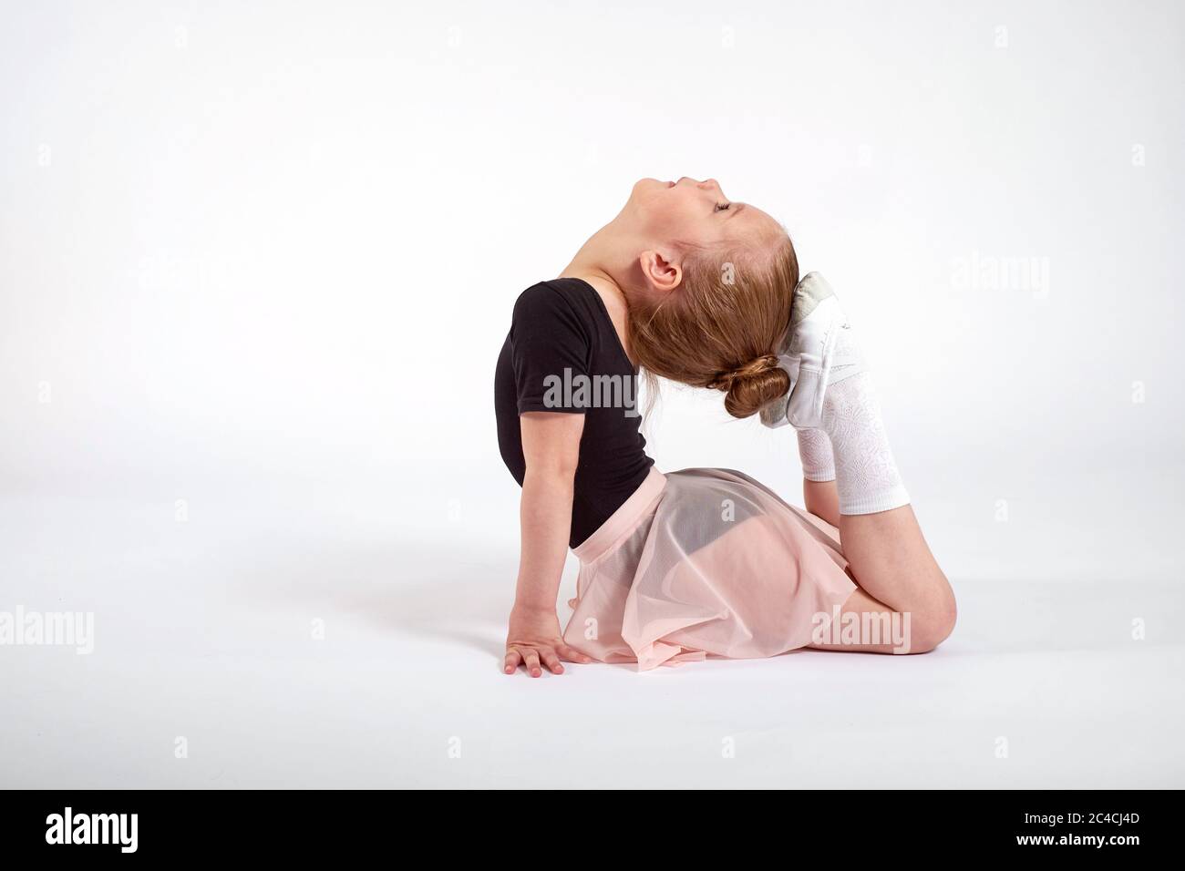 Little girl doing stretching and gymnastic exercises on a white ...