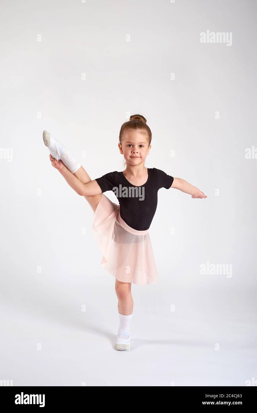 Little girl doing stretching and gymnastic exercises on a white ...