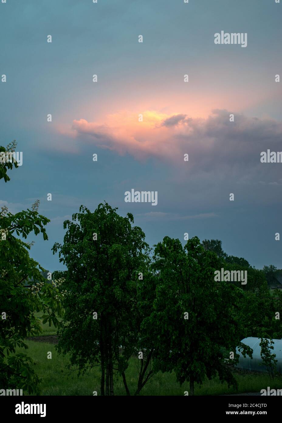 summer landscape with a colorful sunset over the roof, view through the ...