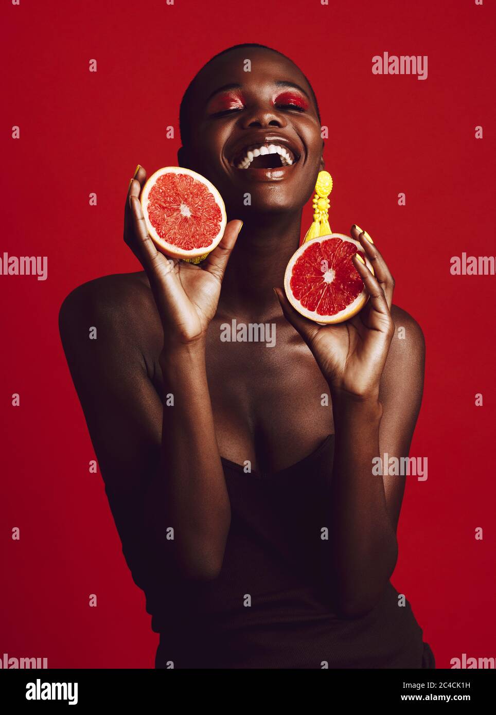 Smiling african woman holding grapefruit. Female model with buzz cut ...