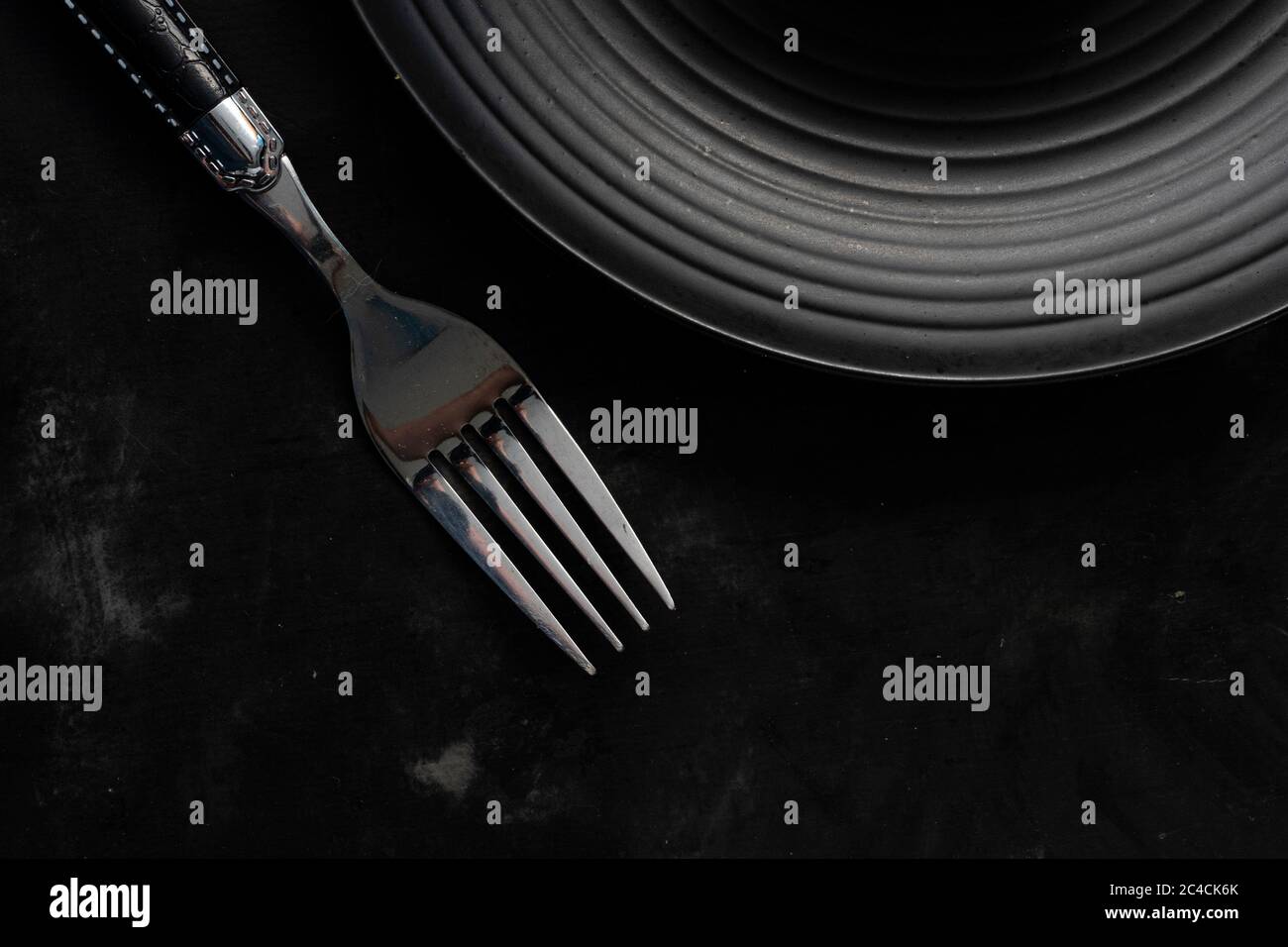 selective focus, kitchen utensils, black round plate with a black fork ...