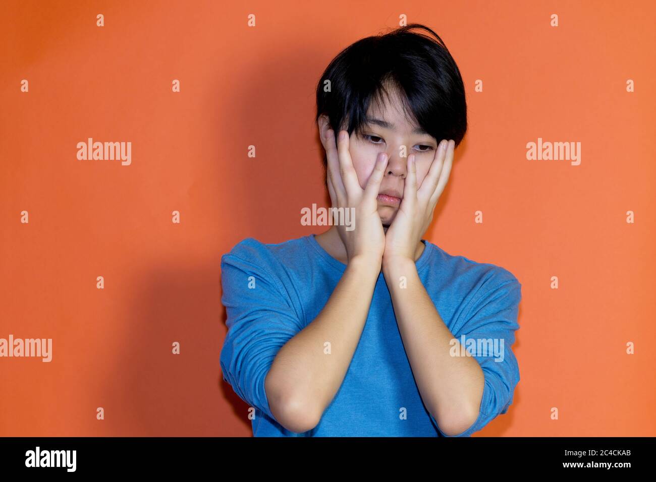 Shocked chinese young adult man with blue shirt isolated on orange ...