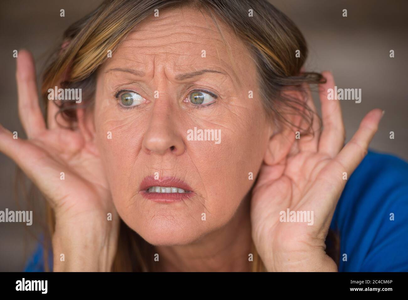 Portrait attractive mature woman with hands at ears listening with ...