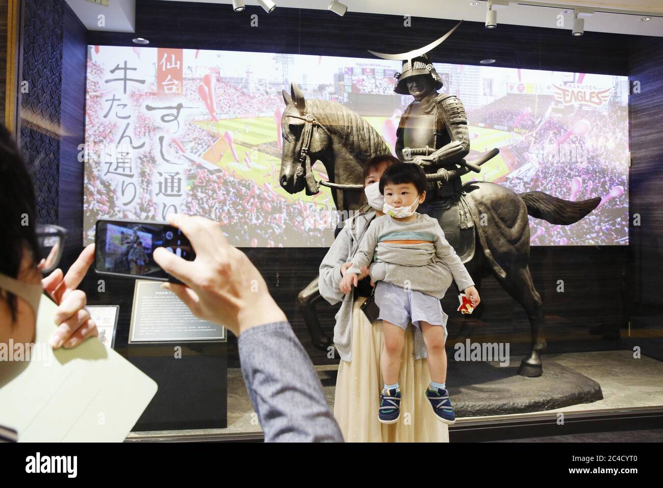 A mother and child pose for a photo in front of an equestrian statue of ...