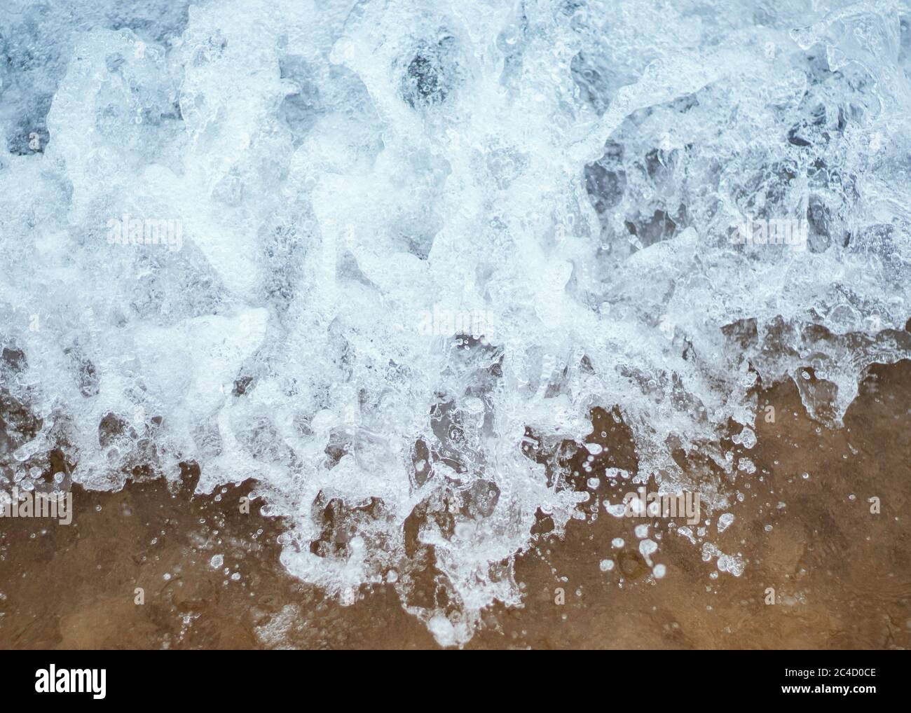 Macro shot of the sea splashing onto the beach sand Stock Photo - Alamy