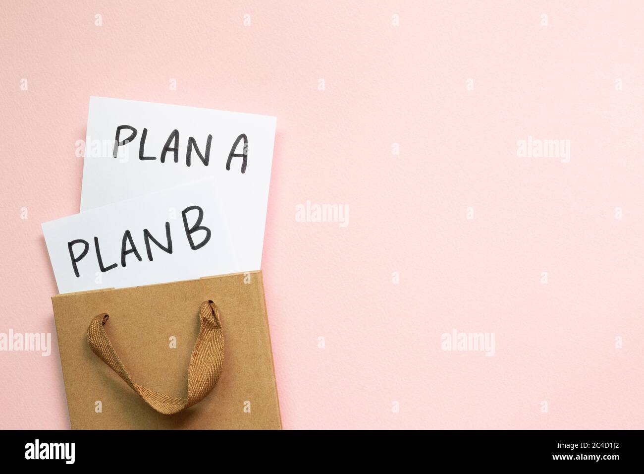 Plan A and plan B in a kraft paper bag on pink background. Business ...