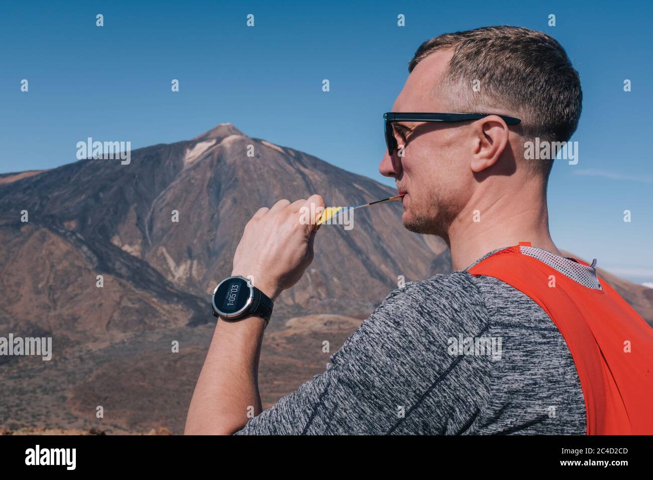 Portrait of young man eat sports nutrition energy gel while sitting and ...
