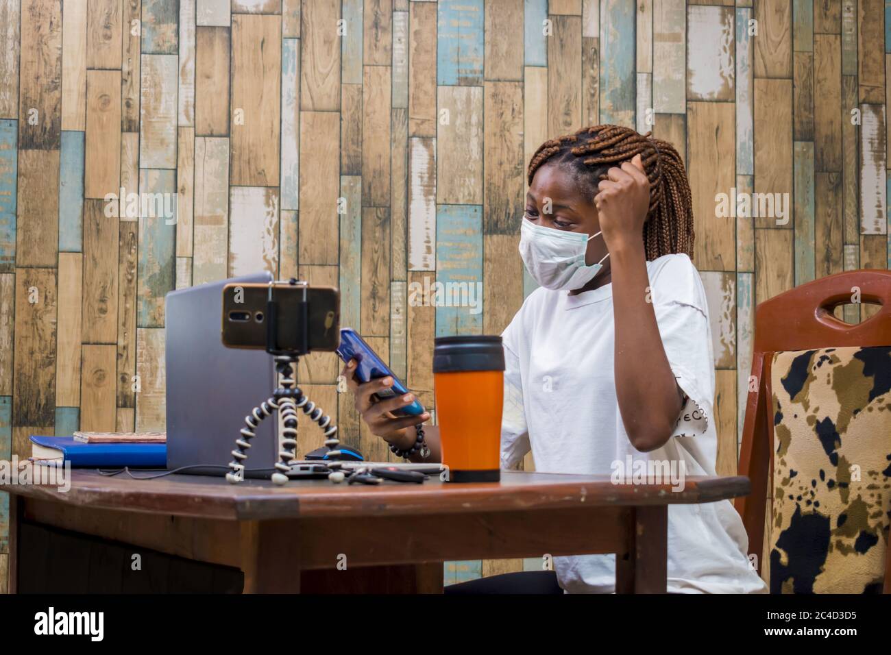African female recording herself while typing on the laptop on a wooden ...