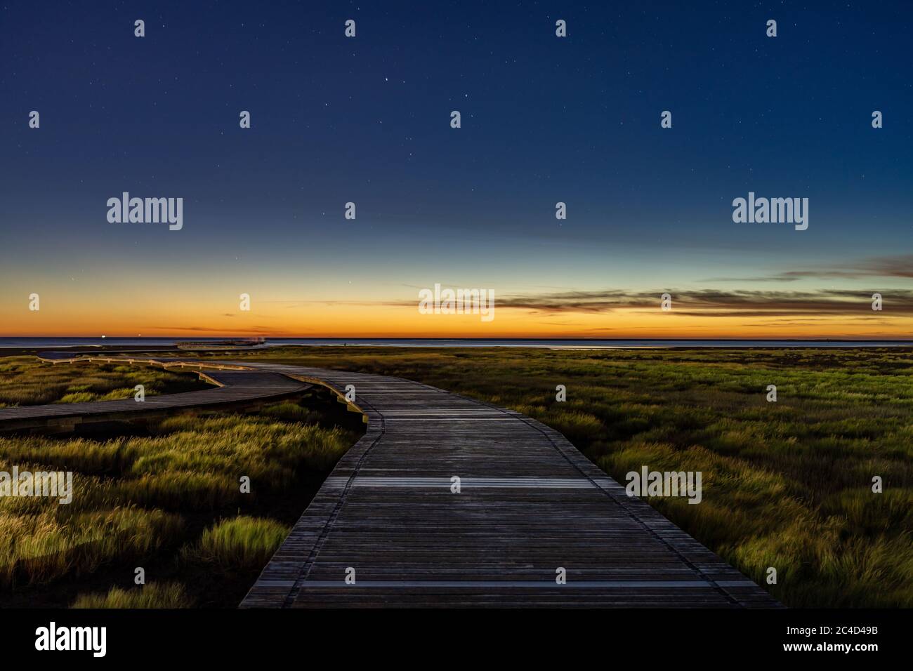 Sea shore scenic walkway bridge in wetlands under sunset glow with rosy ...
