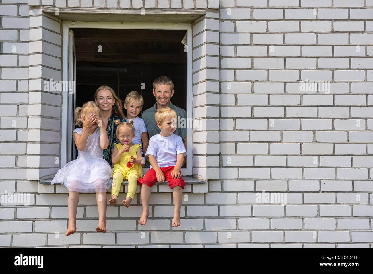 A large large family poses from the window of their home Stock Photo ...