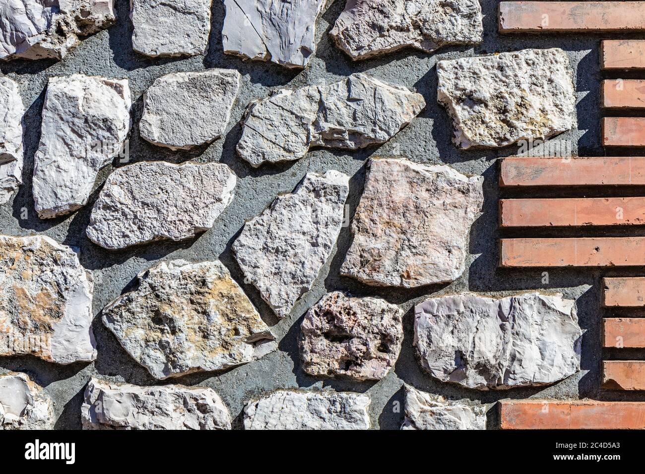 Wall made of cement and irregularly shaped stones. Architectural detail ...