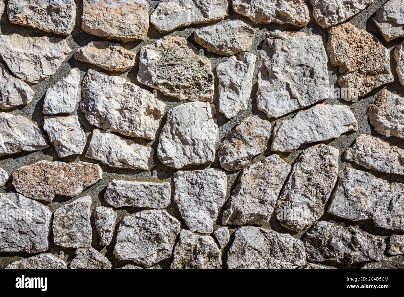 Wall made of cement and irregularly shaped stones. Architectural detail ...
