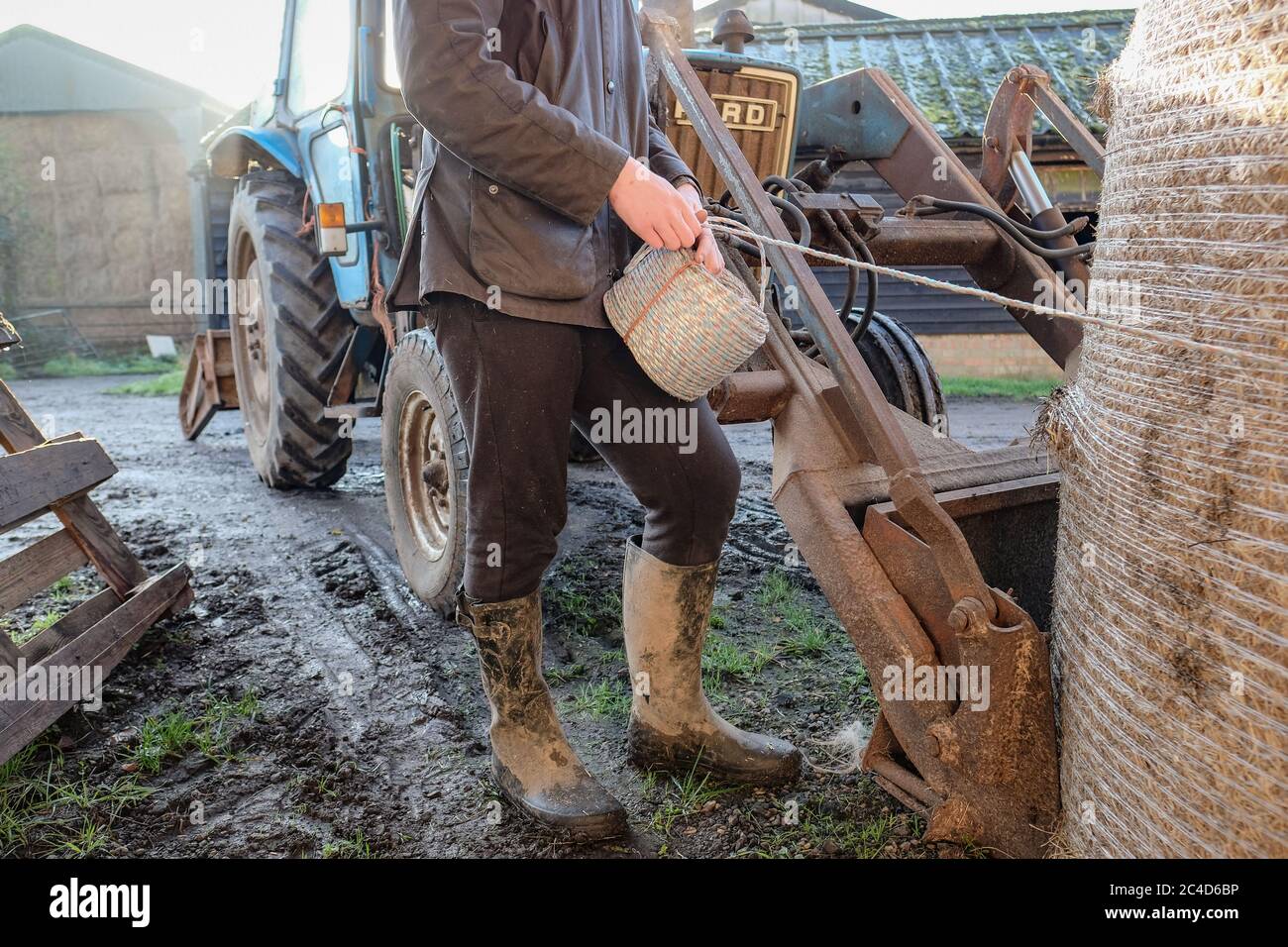 Young male farmer seen wrapping a large agricultural bale of straw ...