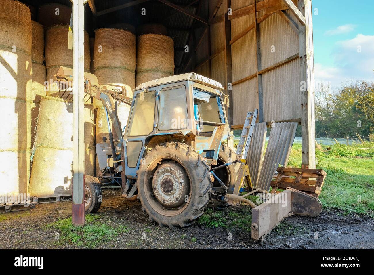 Farmer seen in his tractor, about to pick up a very large and heavy ...