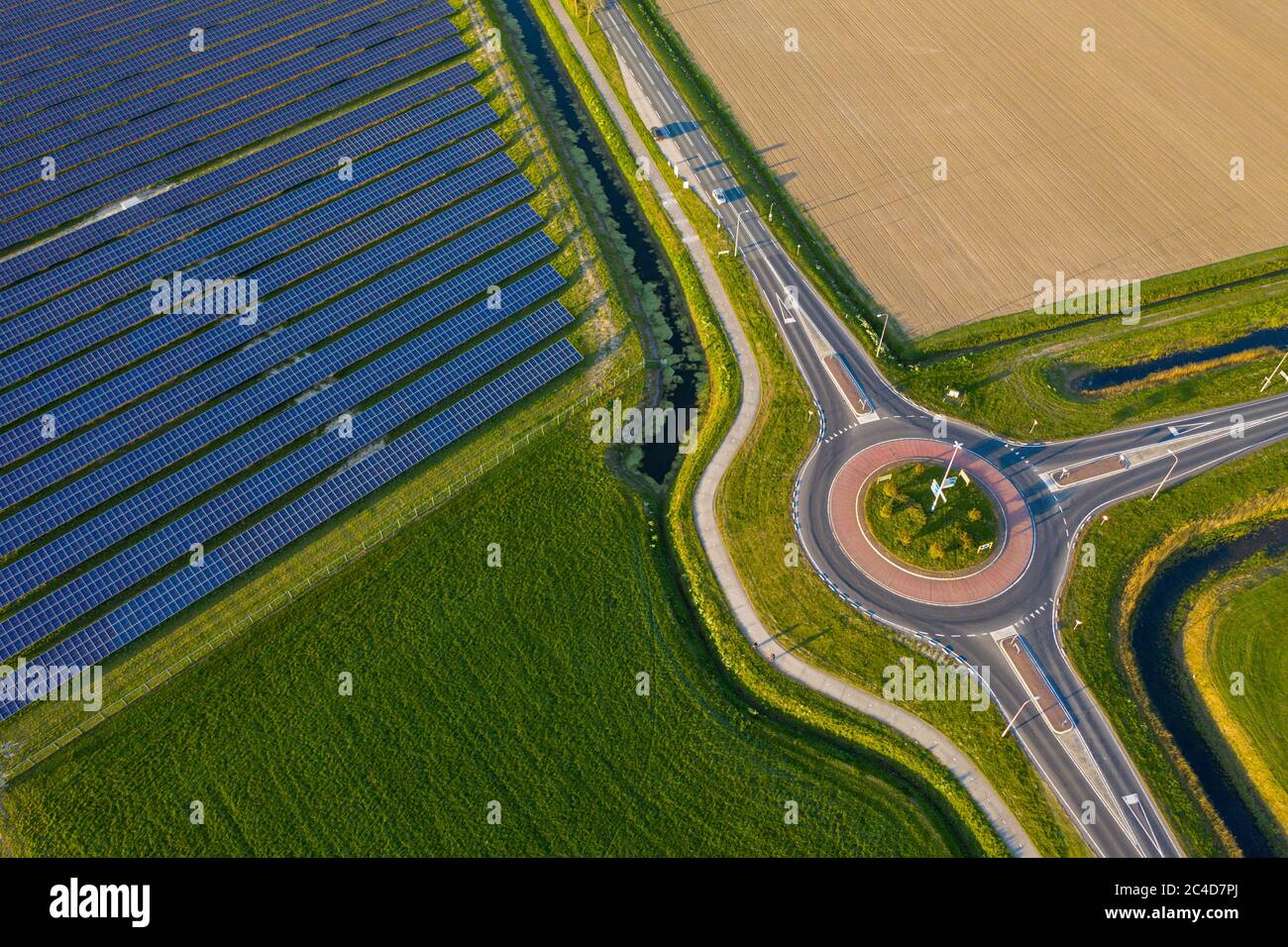 Aerial shot of a field of solar panels with a round road intersection ...