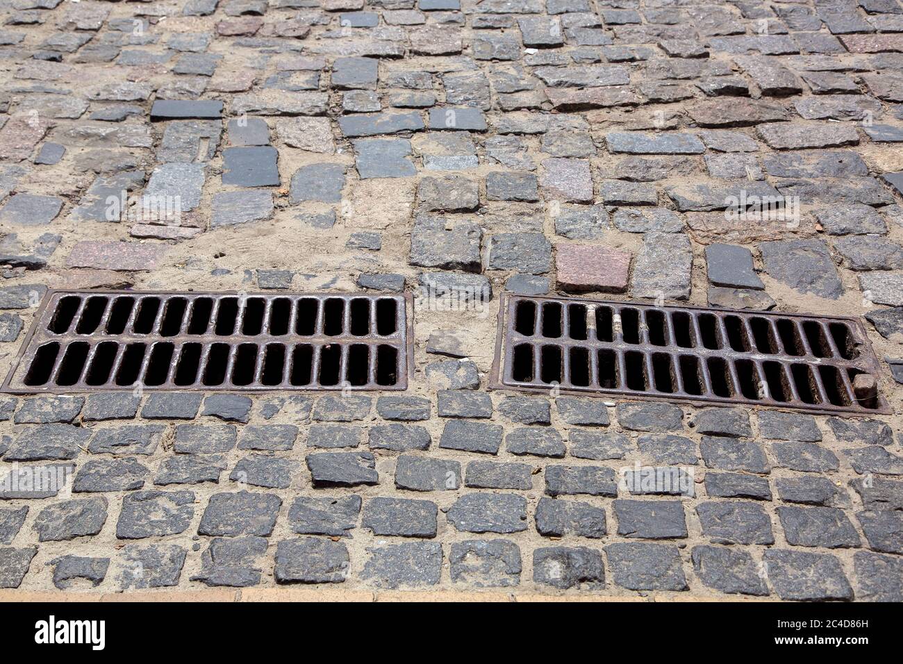 the iron grates of the drainage system hatch on the road paved with ...