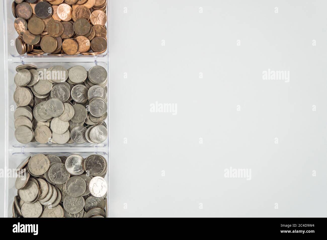 Overhead closeup shot of coins in different containers on a white ...