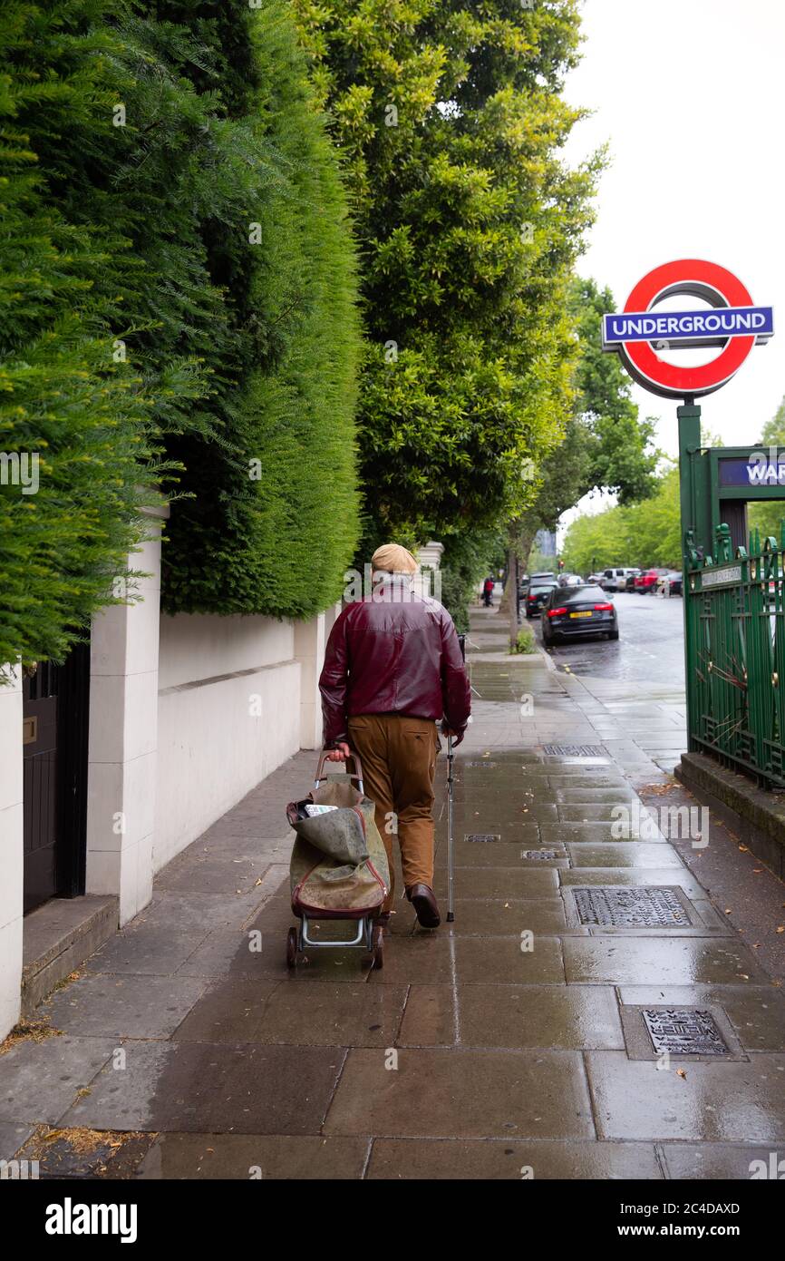 An old man walks alongside the street. and the tube in London, United ...