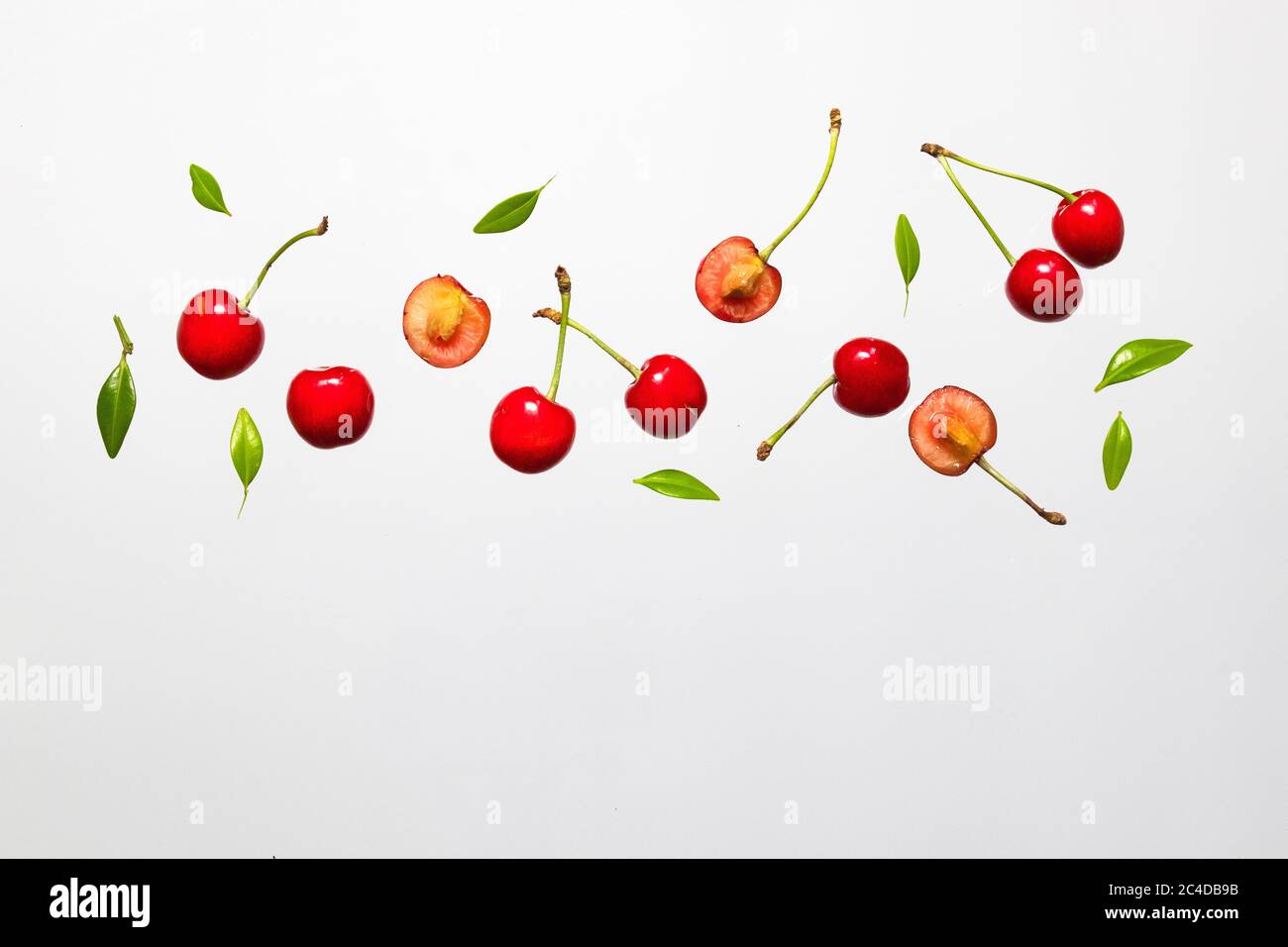 Falling organic fresh ripe cherries with green leaves isolated on a ...