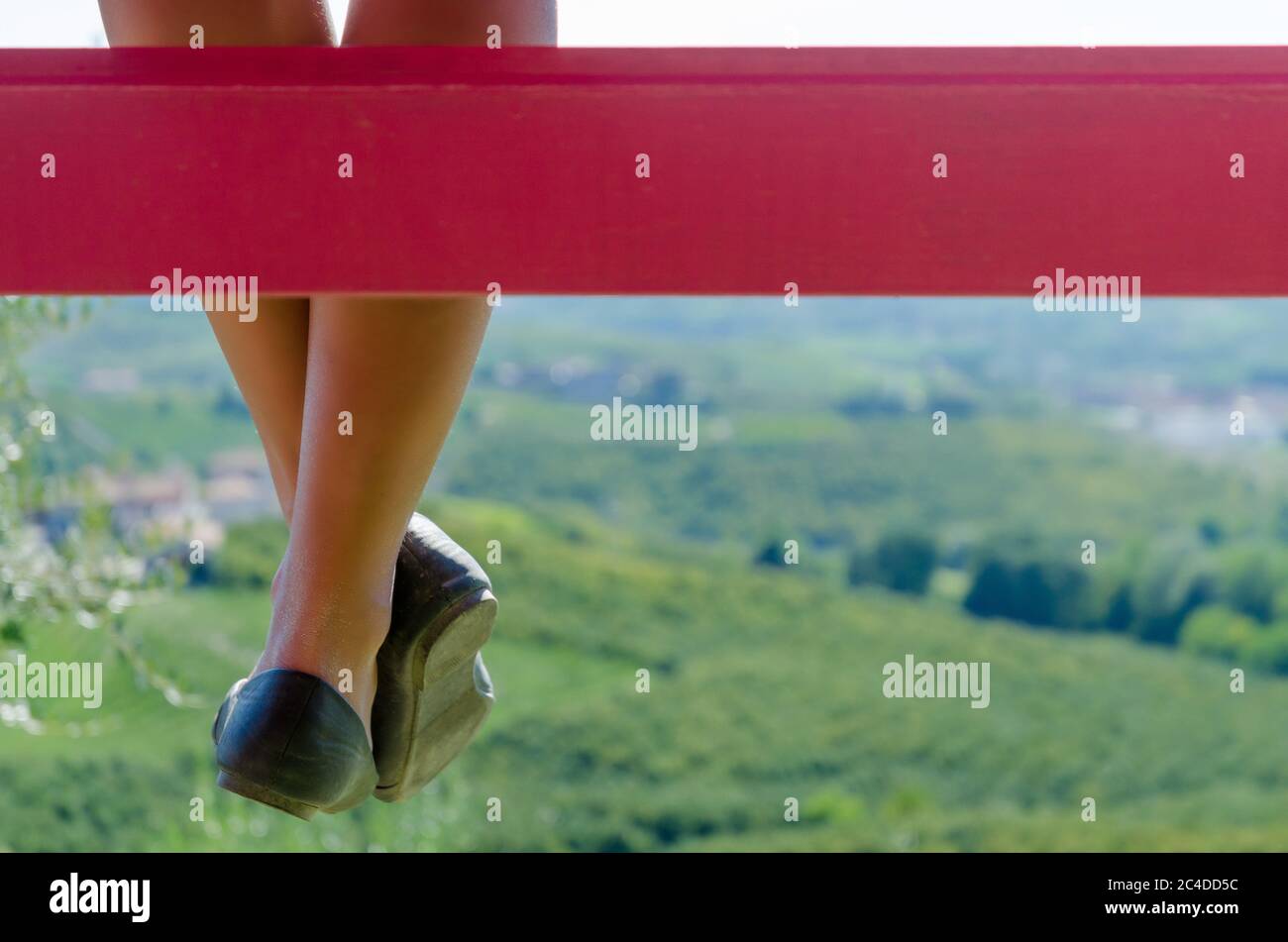 Woman's legs down from a bench with green natural landscape in the ...