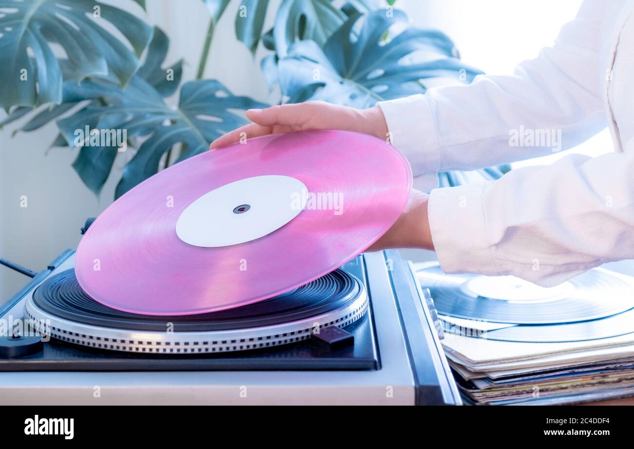 Vintage record player and hand holding pink vinyl record on the green ...