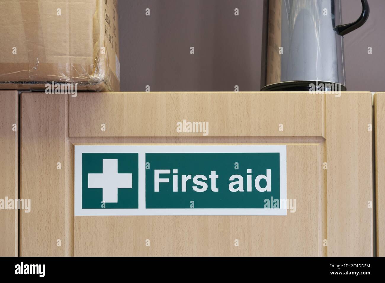 First Aid sign located on an office kitchen cupboard, containing a ...