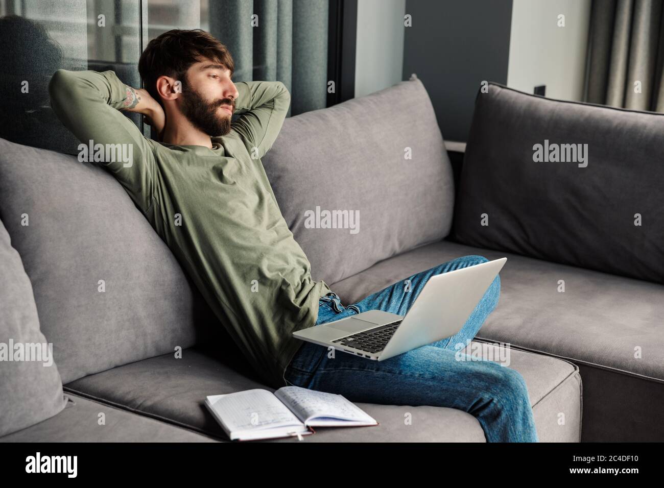 Image of relaxed bearded man in casual wear resting while working with ...