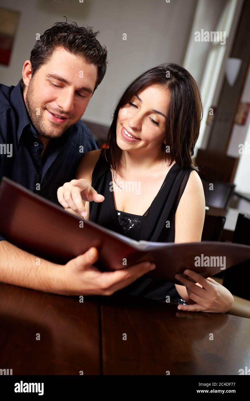 Happy couple in restaurant looking at menu together Stock Photo - Alamy
