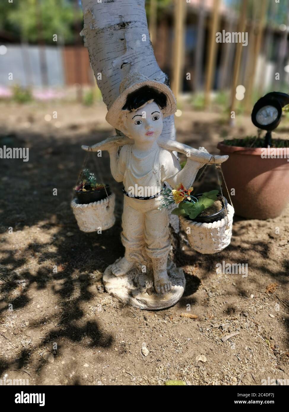 Closeup shot of a white garden statue of a boy holding flower pots ...