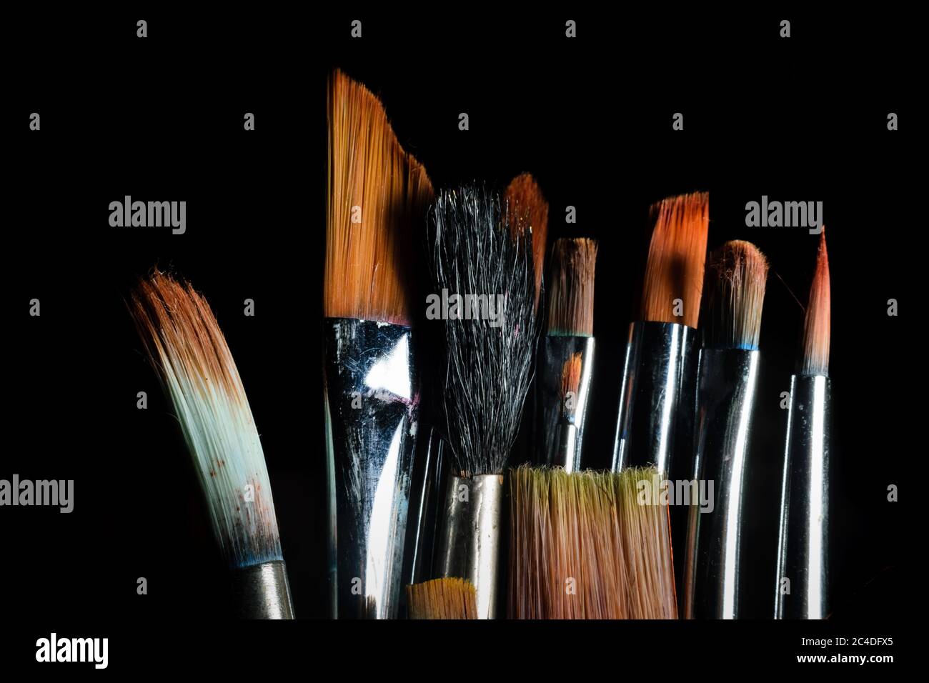 Paint brushes of different size are kept side by side in a dark ...