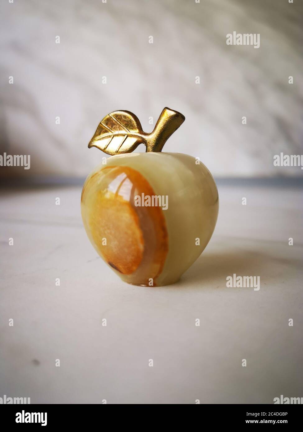Shot of a brown marble apple with gold stem presented on the floor ...