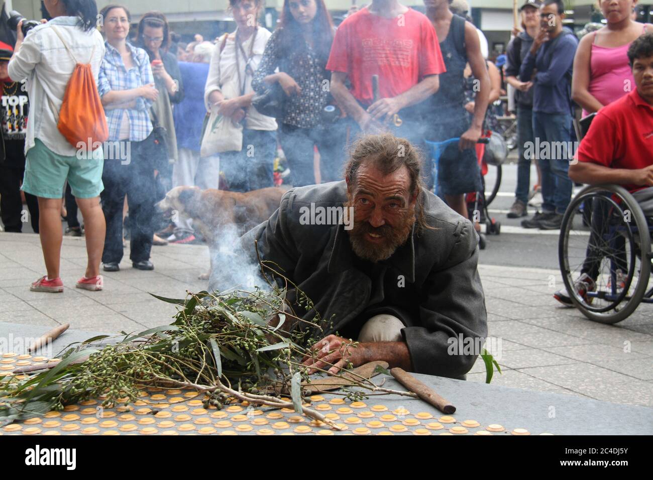 A man does a smoking ceremony outside Redfern Police station in front ...