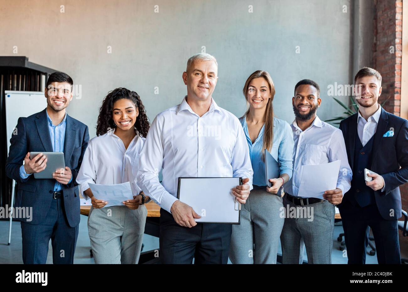 Group Of Colleagues Smiling To Camera Standing In Office Stock Photo ...
