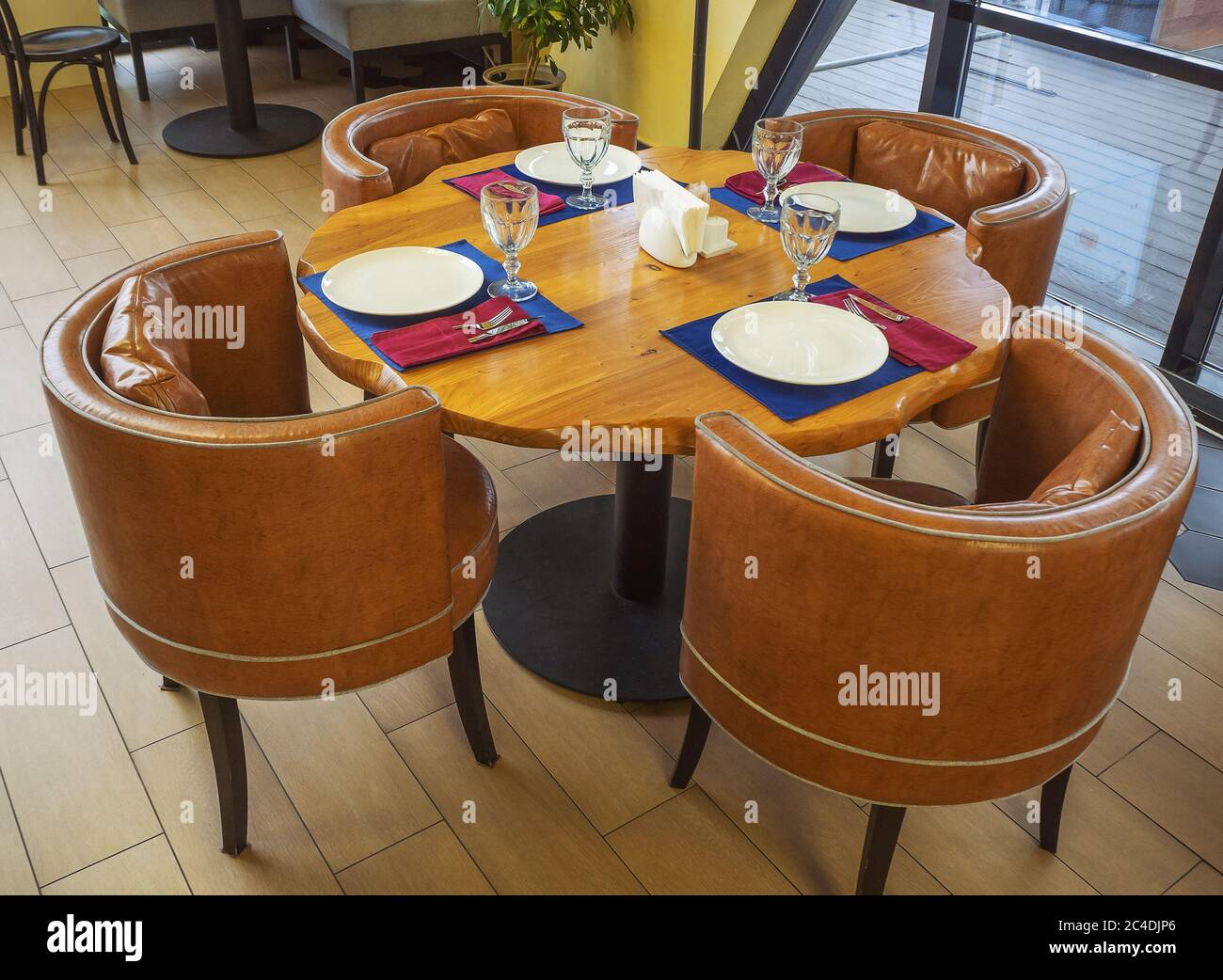 Round orange served table with leather armchairs around in cafe ...