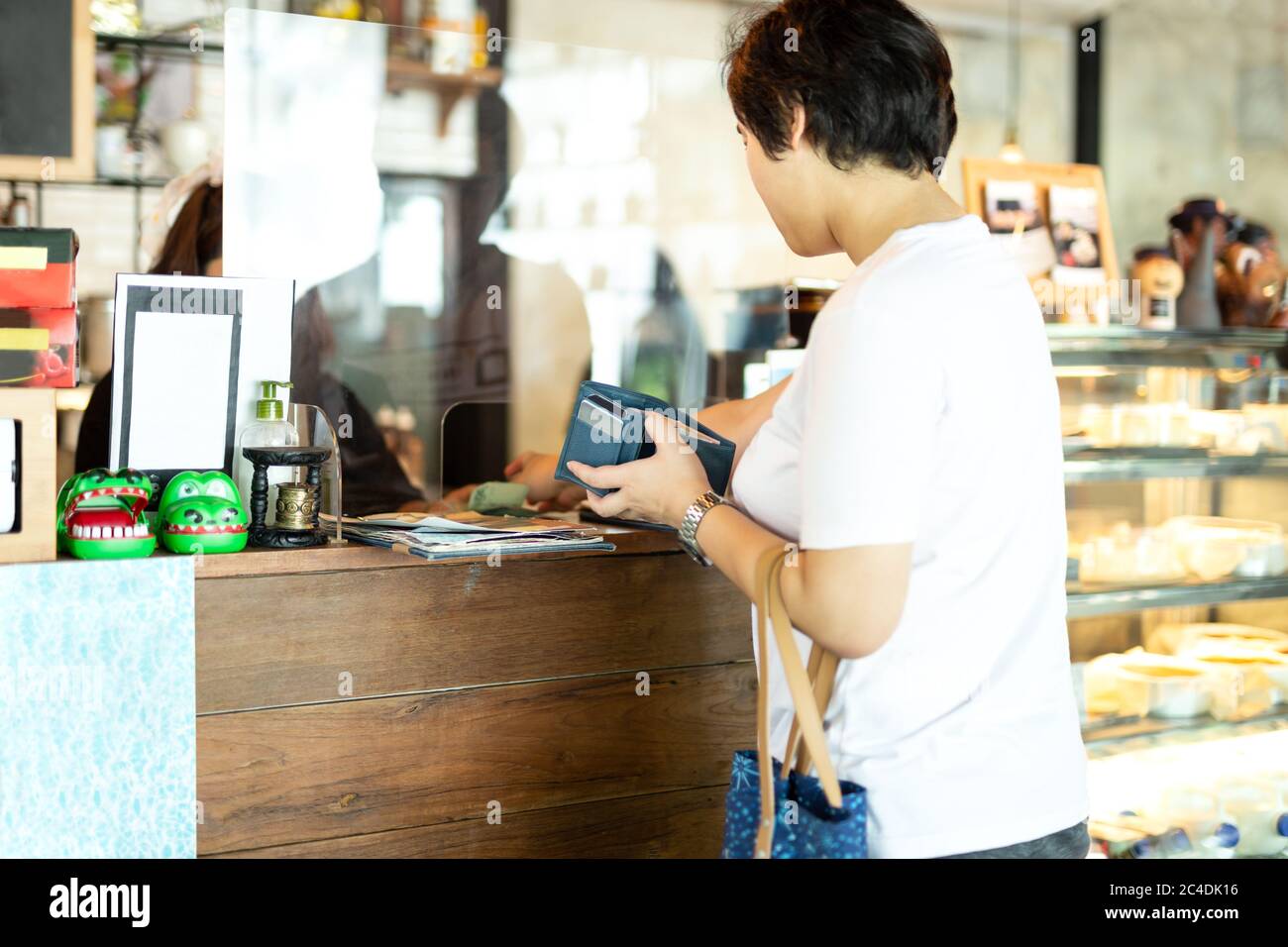 New normal woman paying cash money in cafe with partition shield ...
