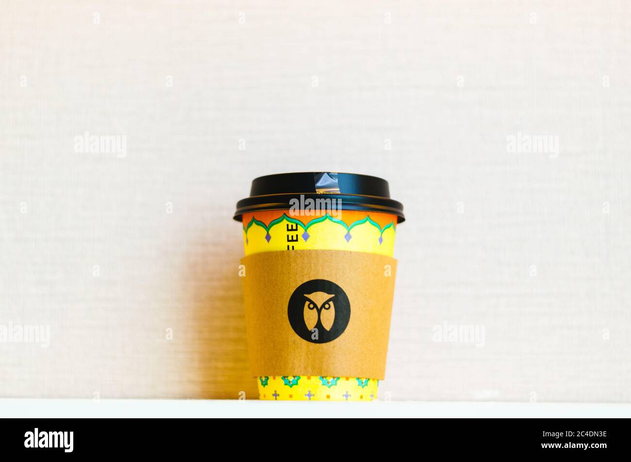 A yellow take away cup of coffee with the Maxx Coffee chain owl logo in ...
