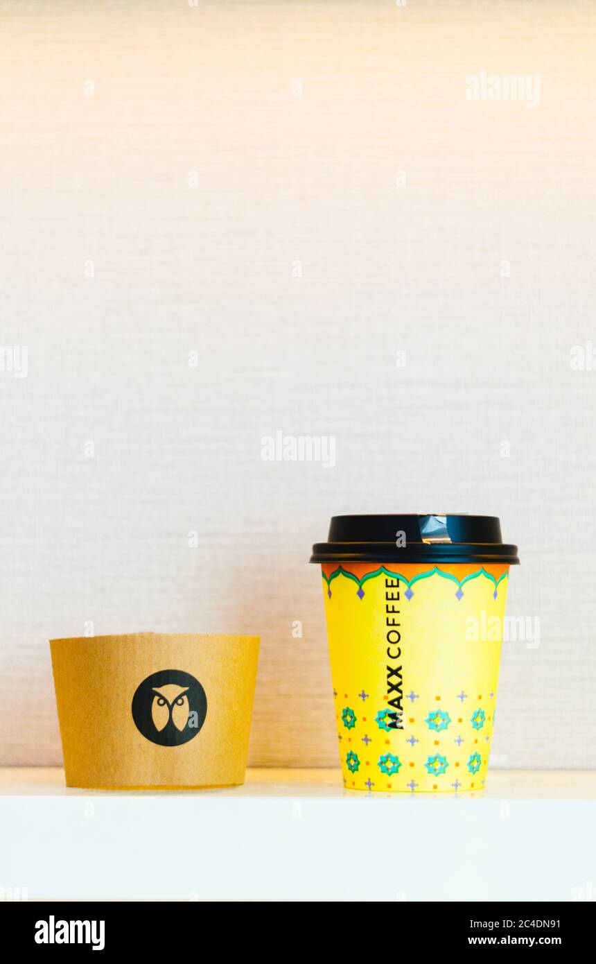 A yellow take away cup of coffee with the Maxx Coffee chain owl logo in ...