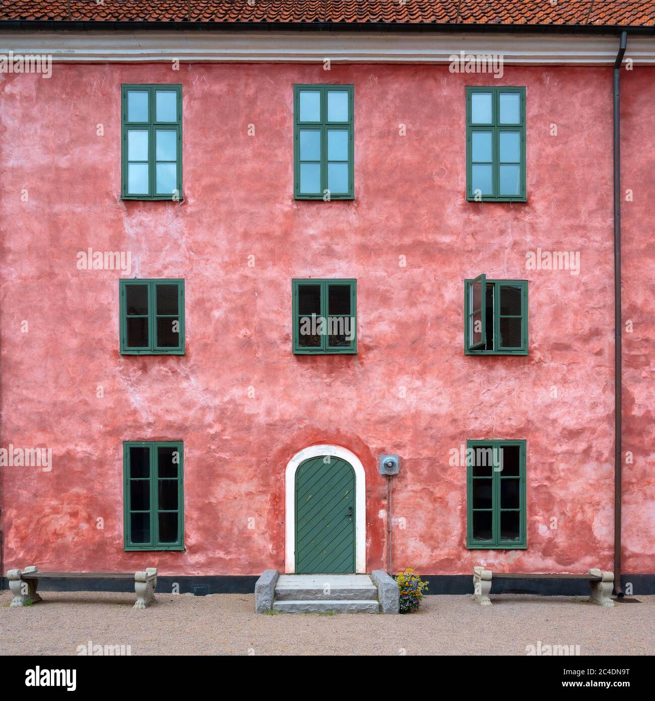 An old pink facade with green windows and a green door in full symmetry ...